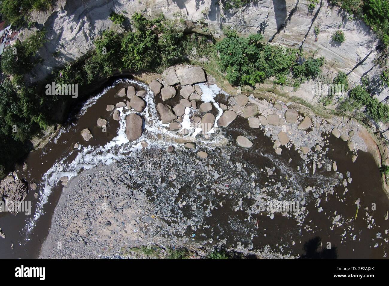 View from the air of a river with polluted water with many houses in ...