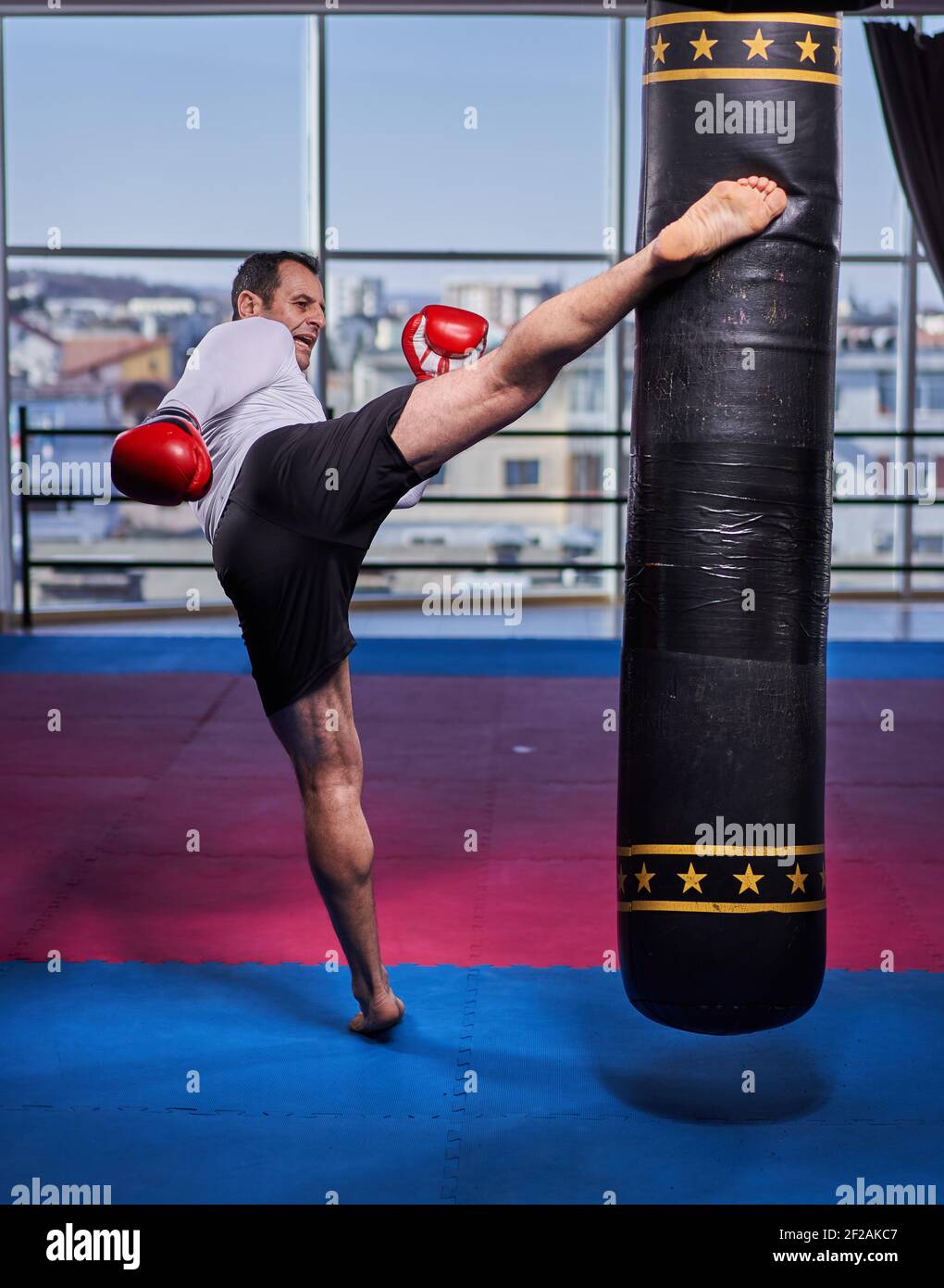Kickboxing fighter hitting the heavy bag in the gym, training for ...