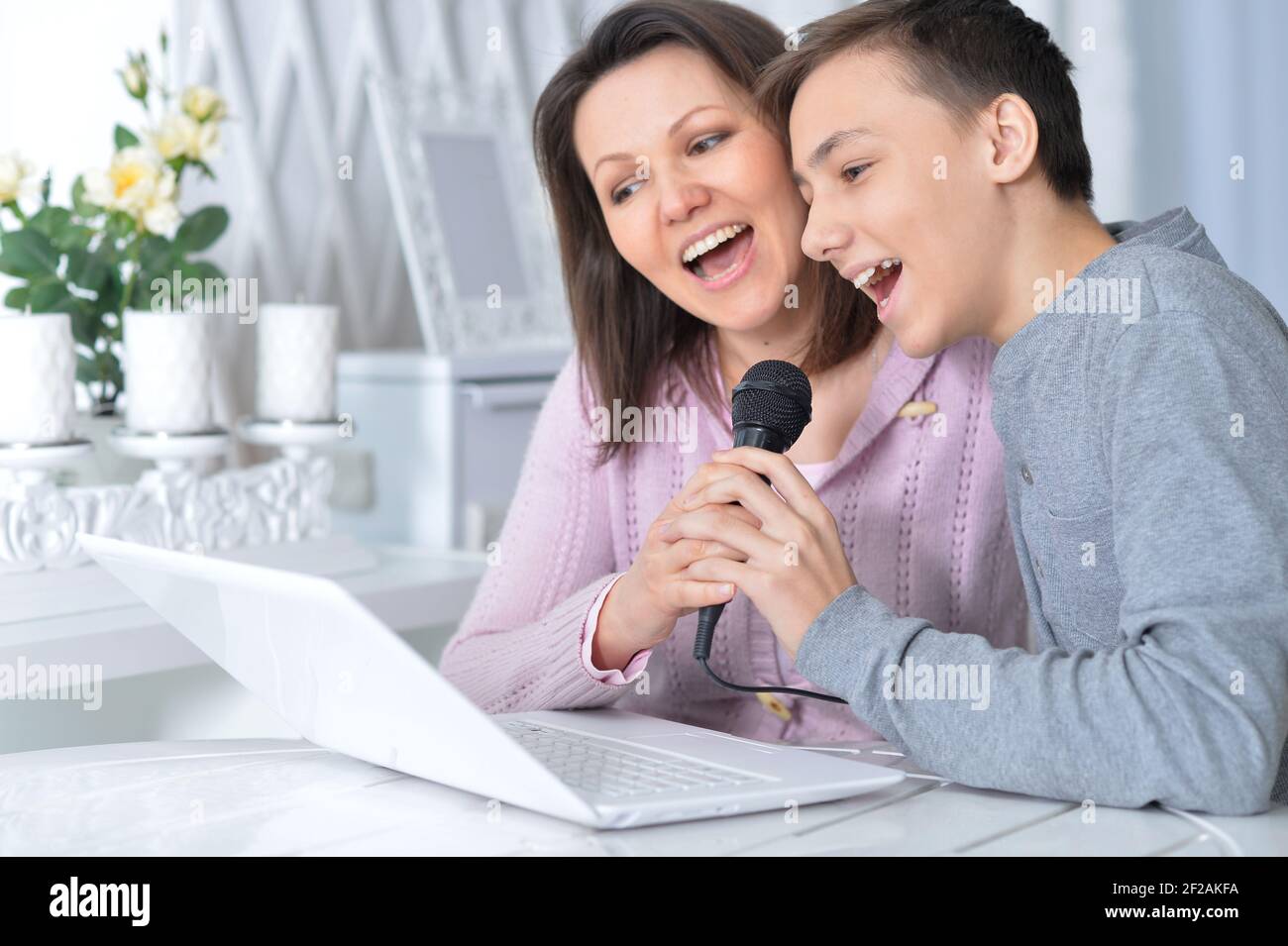 Portrait of emotional mother and son singing karaoke Stock Photo - Alamy