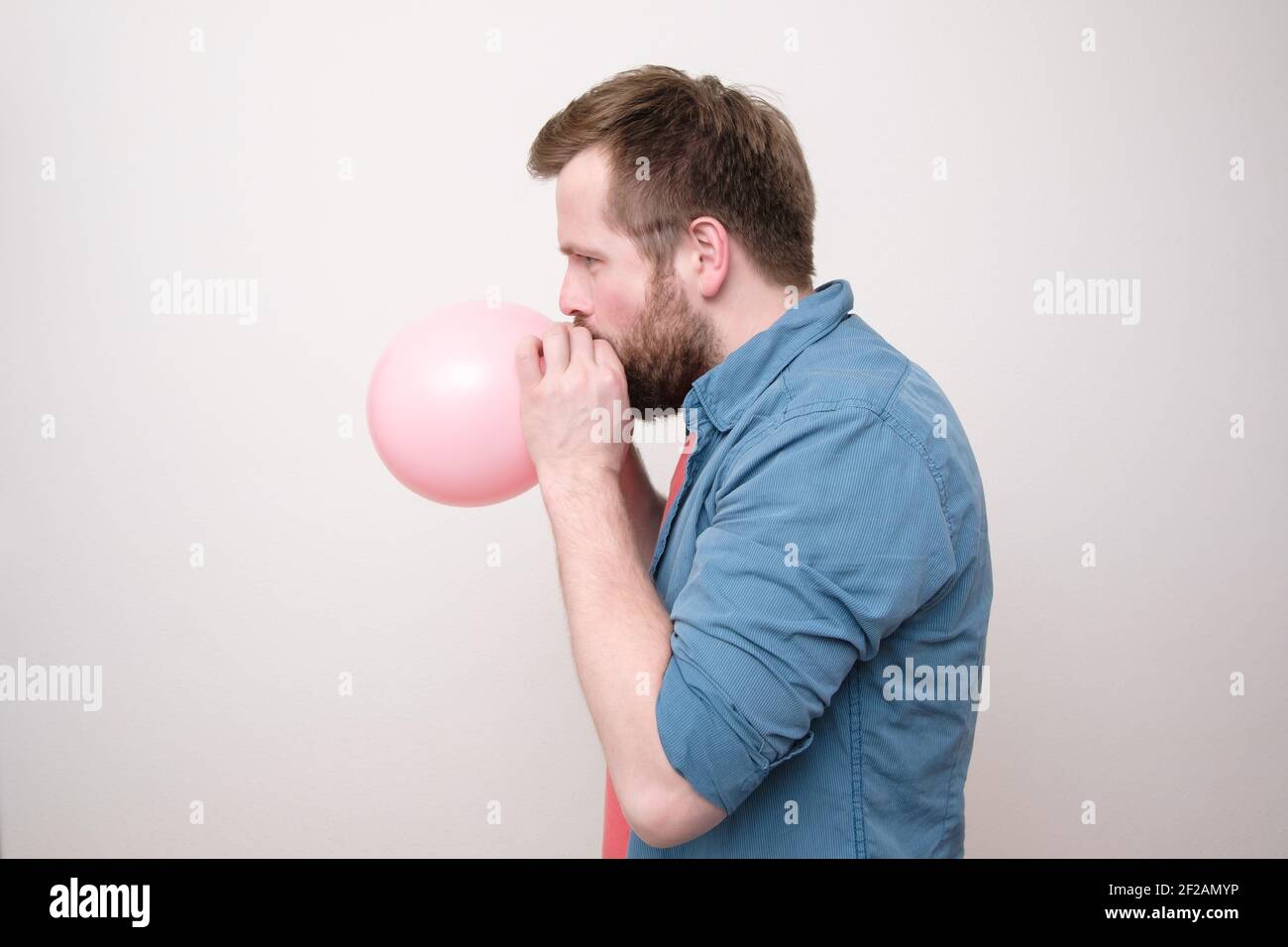 Profile of a Caucasian male inflating a pink balloon. Preparation for ...