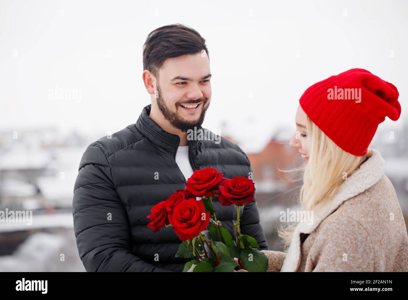 Young handsome guy giving a girl a bouquet of roses on valentine's day ...
