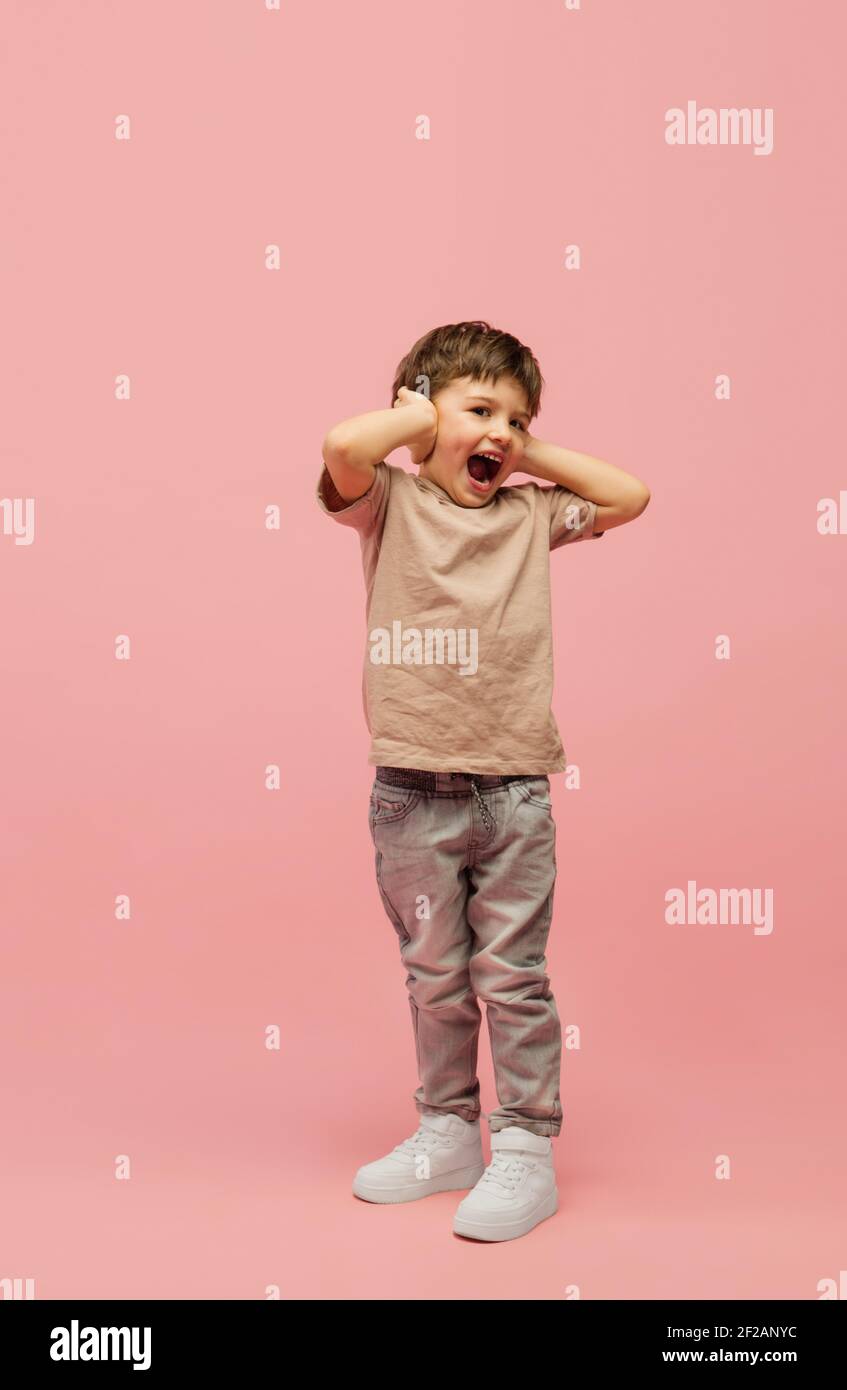Shouting. Happy, smiley little caucasian boy isolated on pink studio ...