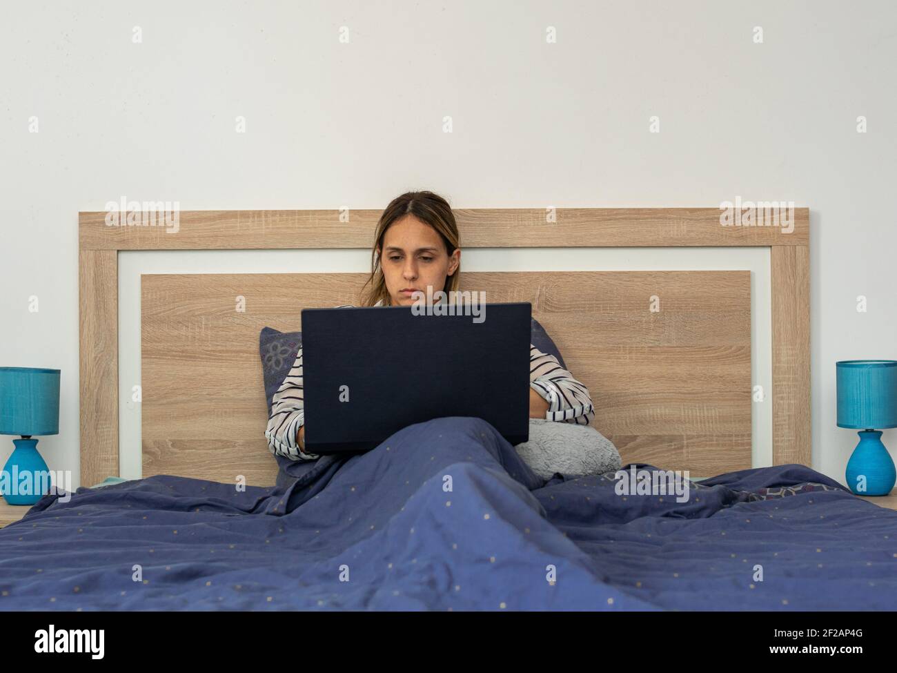 Young woman, in her thirties, teleworking with her laptop, sitting and ...