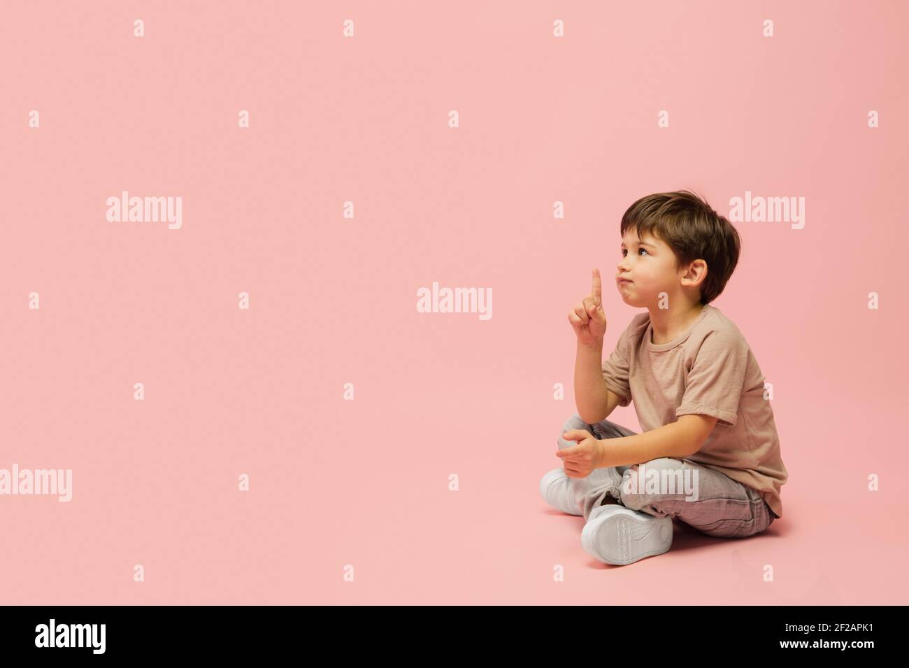Dreaming, pointing. Happy, smiley little caucasian boy isolated on pink ...