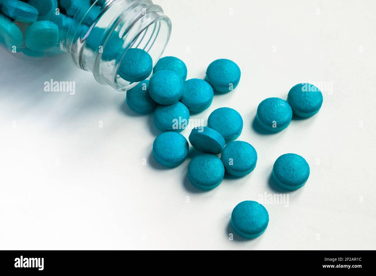 Turquoise blue pills and tablets spilling out from glass pill bottle on ...