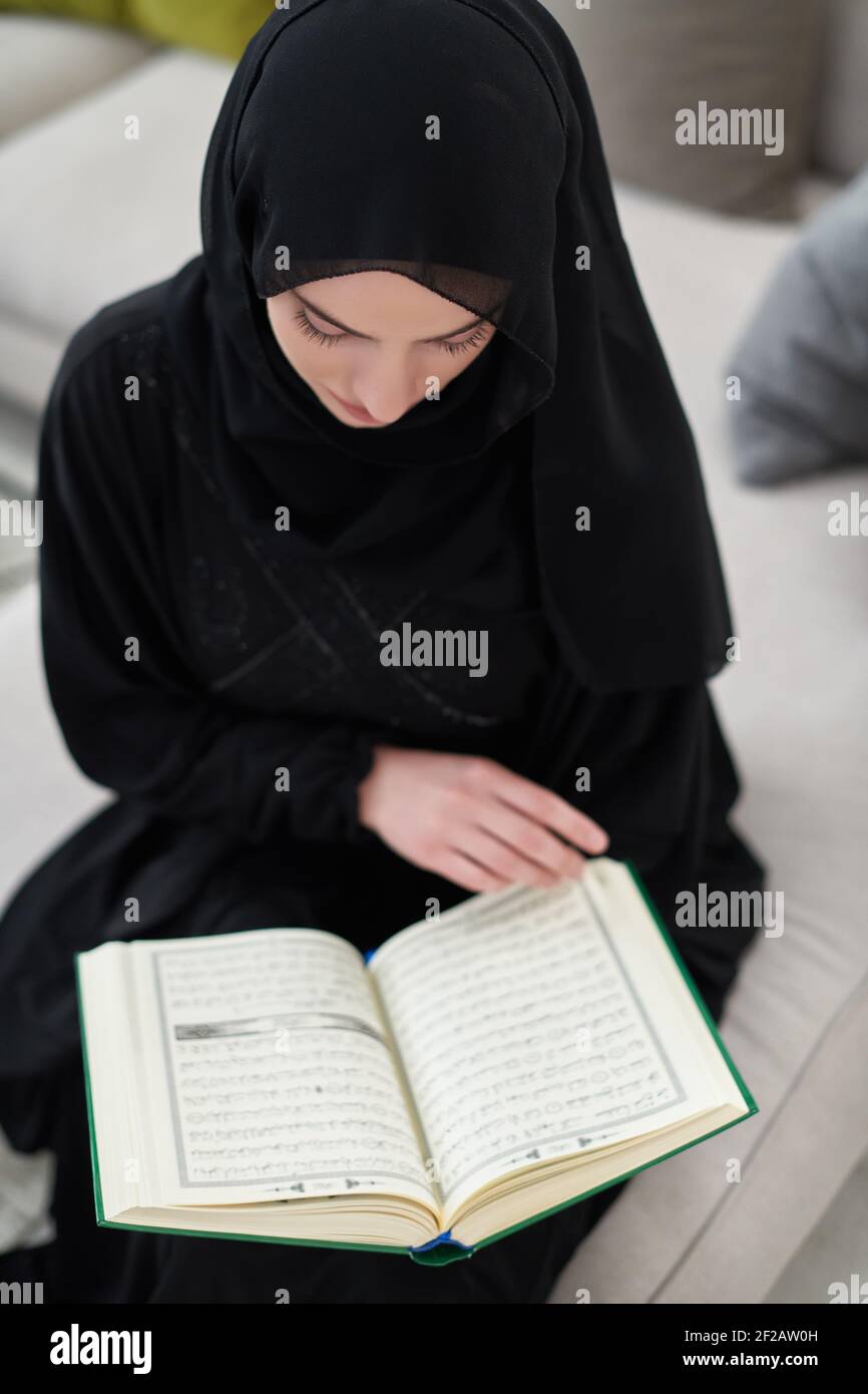 Portrait of young muslim woman reading Quran in modern home Stock Photo ...