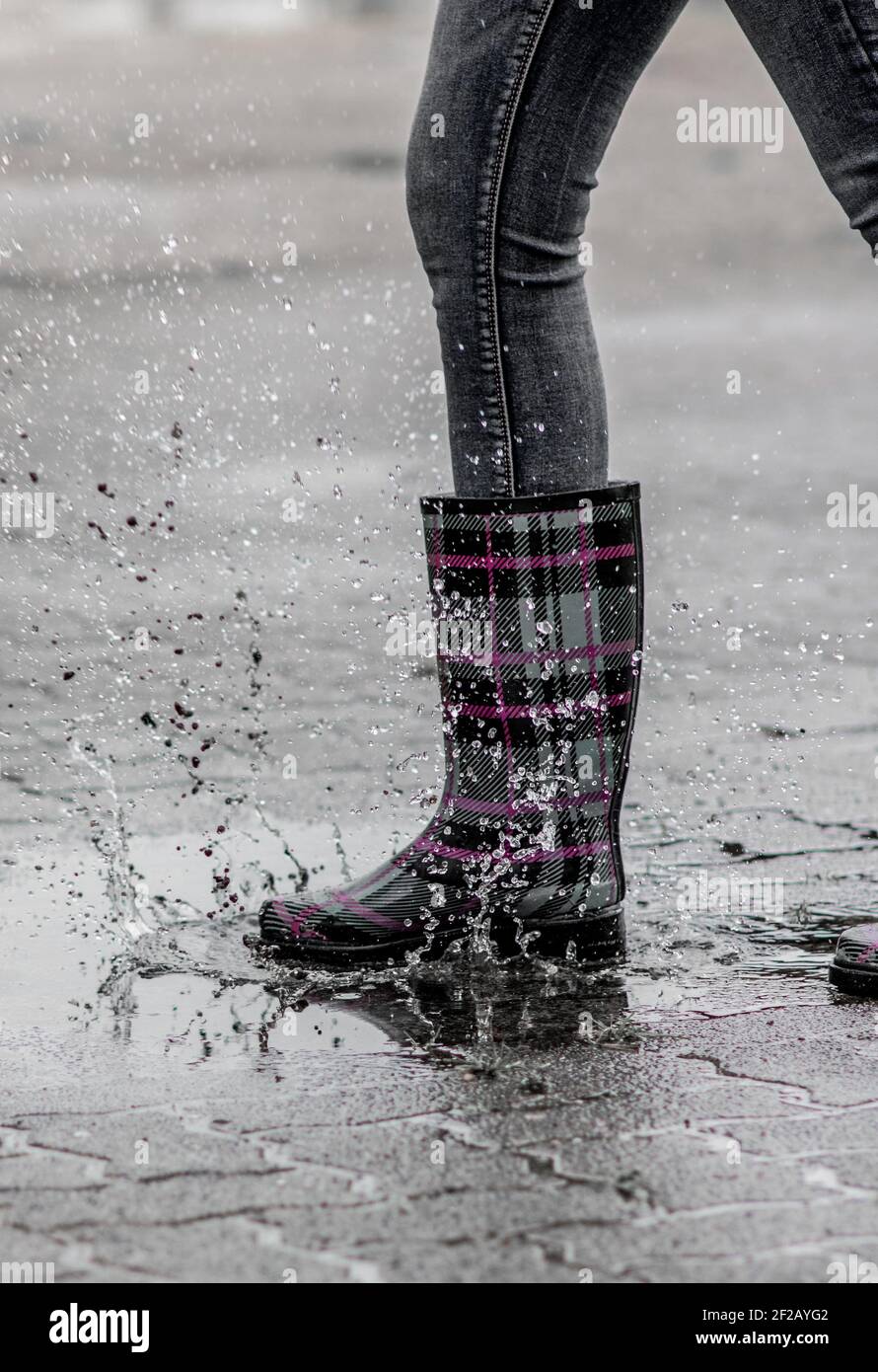 A closeup of a female foot in a stylish rubber boot jumping into a ...