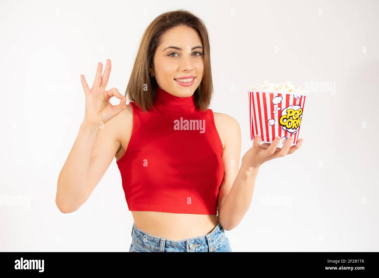 Young beautiful woman eating popcorn with a happy face standing and ...
