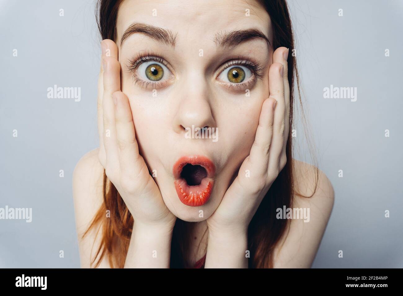 pretty woman with open mouth surprised look emotions hands on face ...