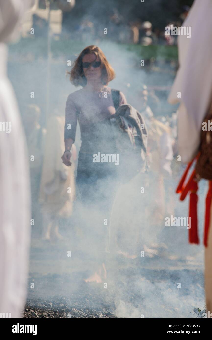 Female western tourist wearing sunglasses firewalks on hot coals at the ...
