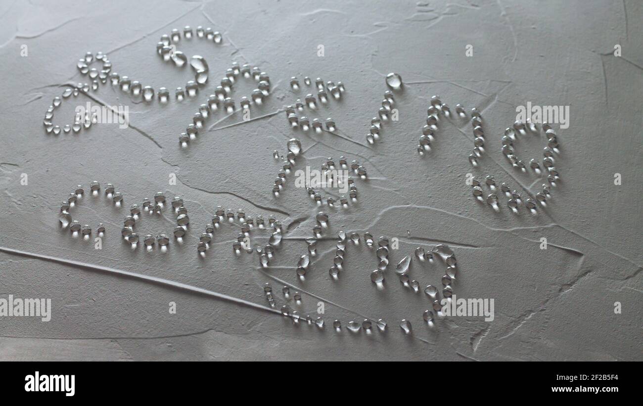 Text Spring is coming, written with water droplets on gray concrete ...