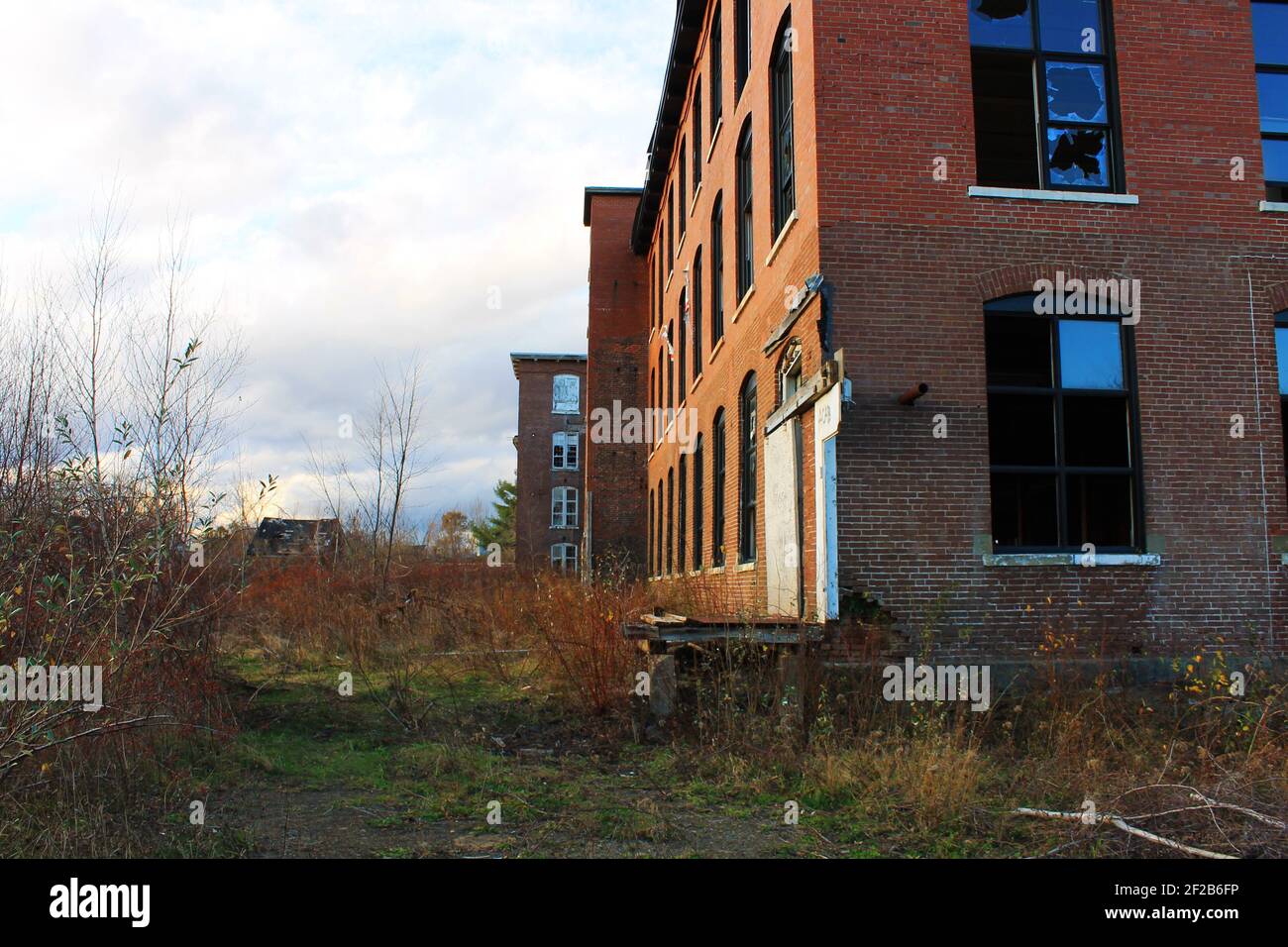 An old, abandoned, brick building that is falling into ruin, with broken windows and overgrown ...