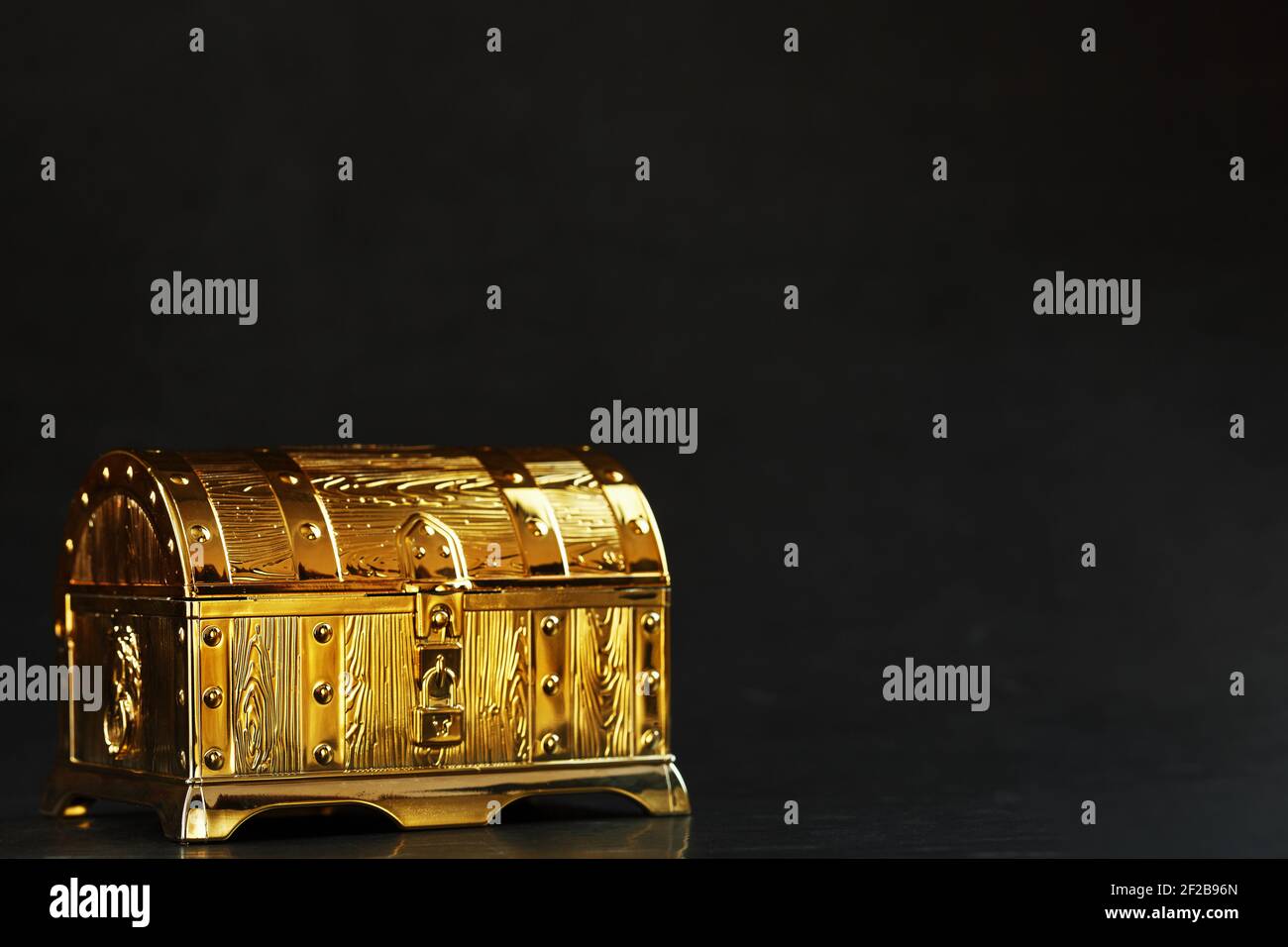 A chest made of gold with jewels on a black background. Free space, the ...
