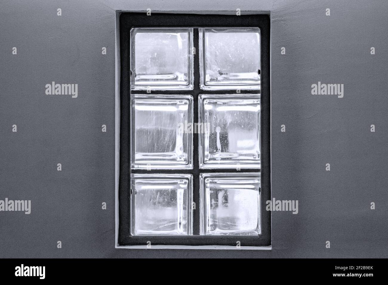 A glass block window in an empty stairwell creates luminous shading and ...