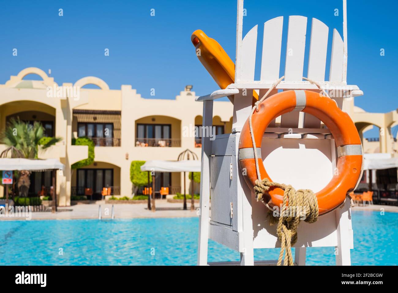 Orange lifebuoy hanging on white Lookout tower near public swimming ...