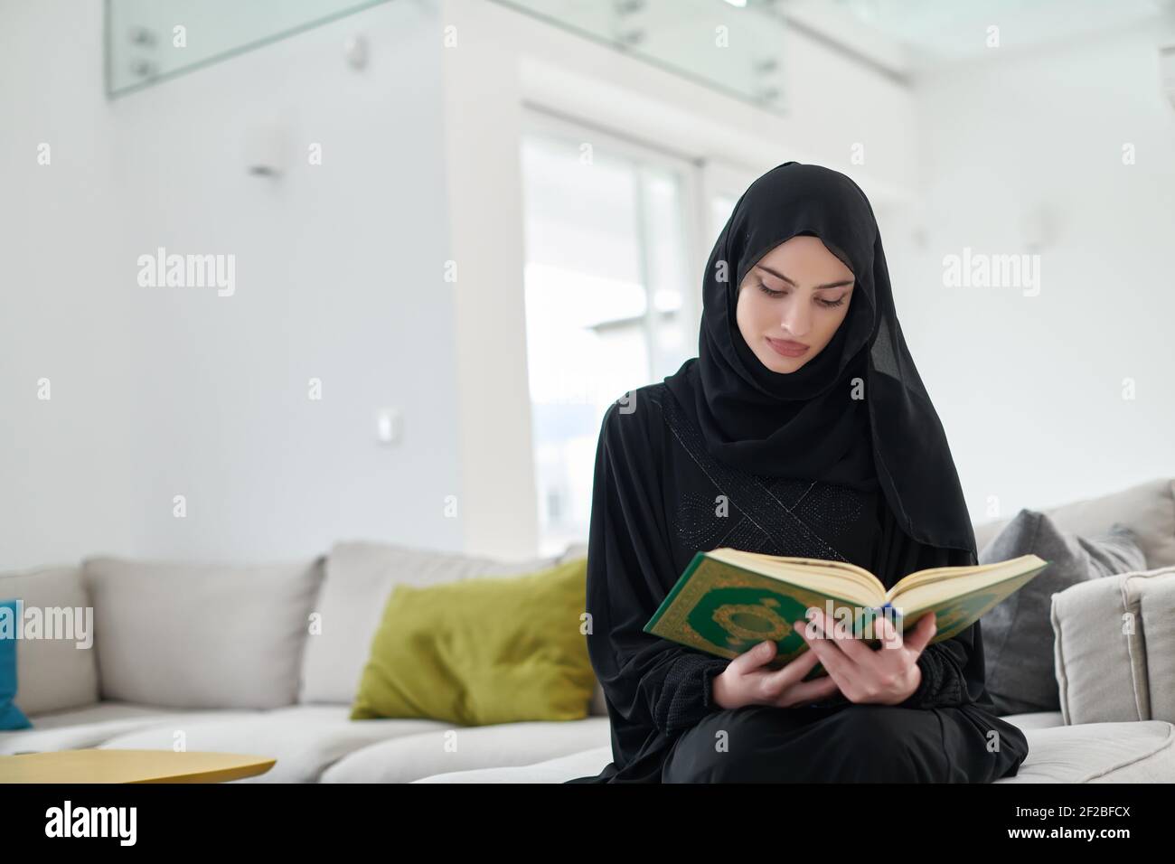 Portrait of young muslim woman reading Quran in modern home Stock Photo ...