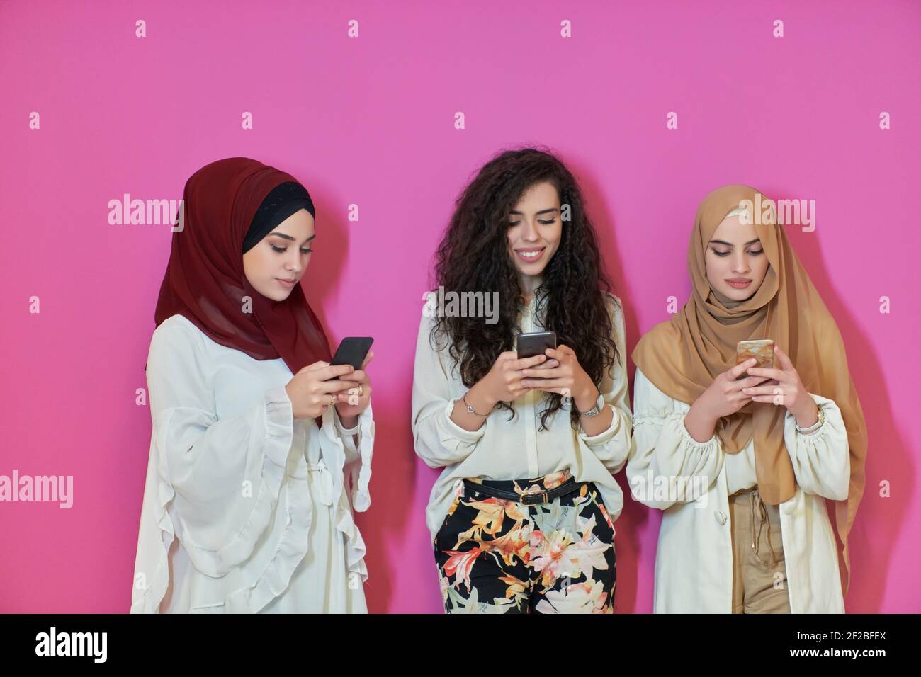 Muslim women using mobile phones isolated on pink background Stock ...
