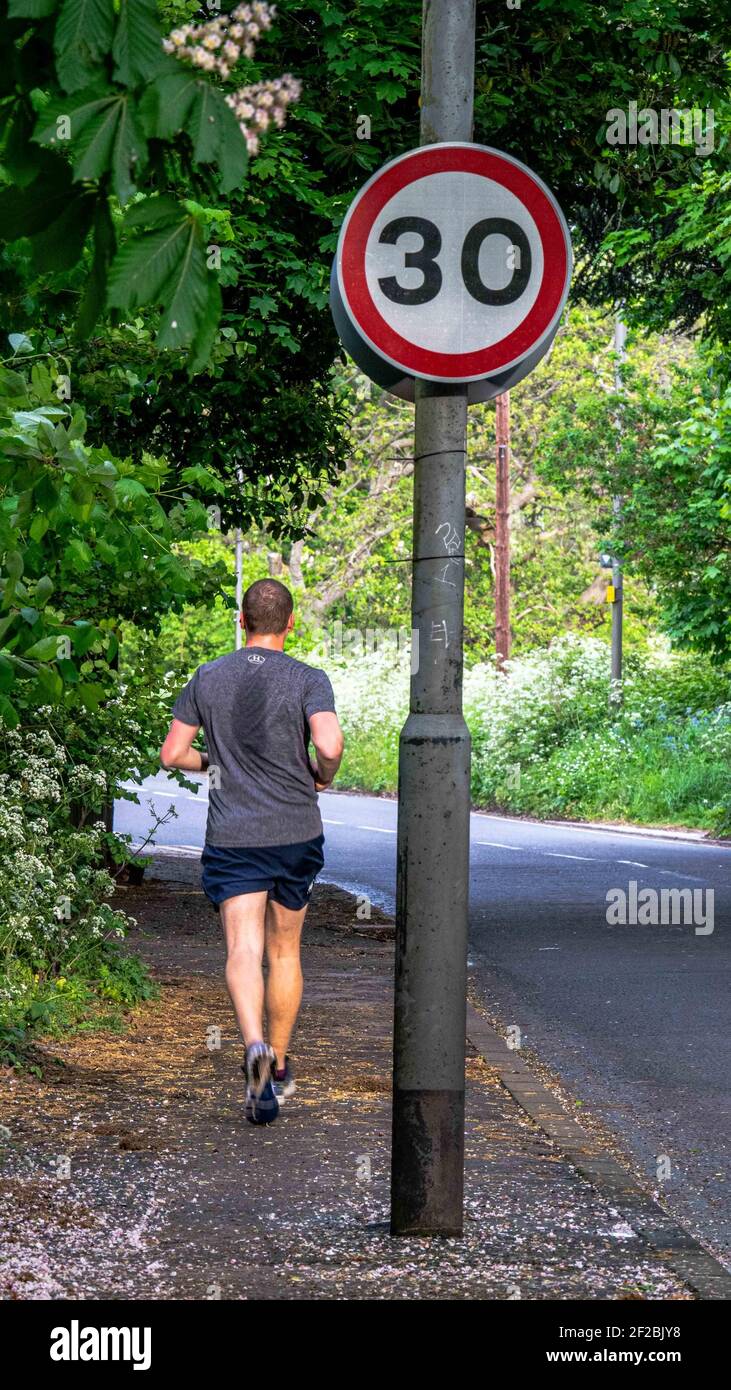 A back view of a young athletic male jogging along the road Stock Photo ...