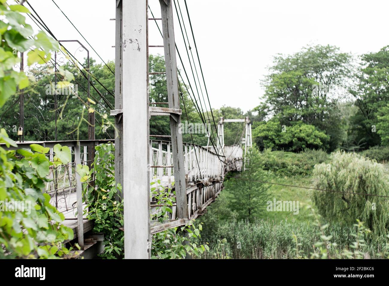 Old iron non-functioning suspension bridge over a dried river side view ...
