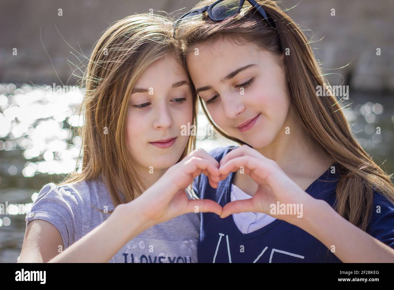 Two teen girls outdoors forming heart shape with their hands Stock ...