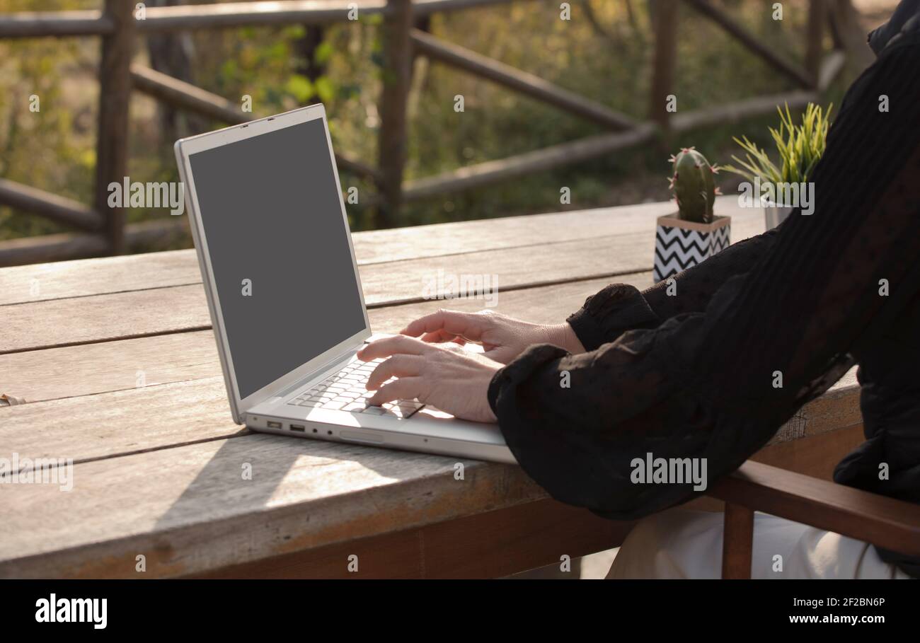woman working virtually, outdoor work table with computer and forest in ...