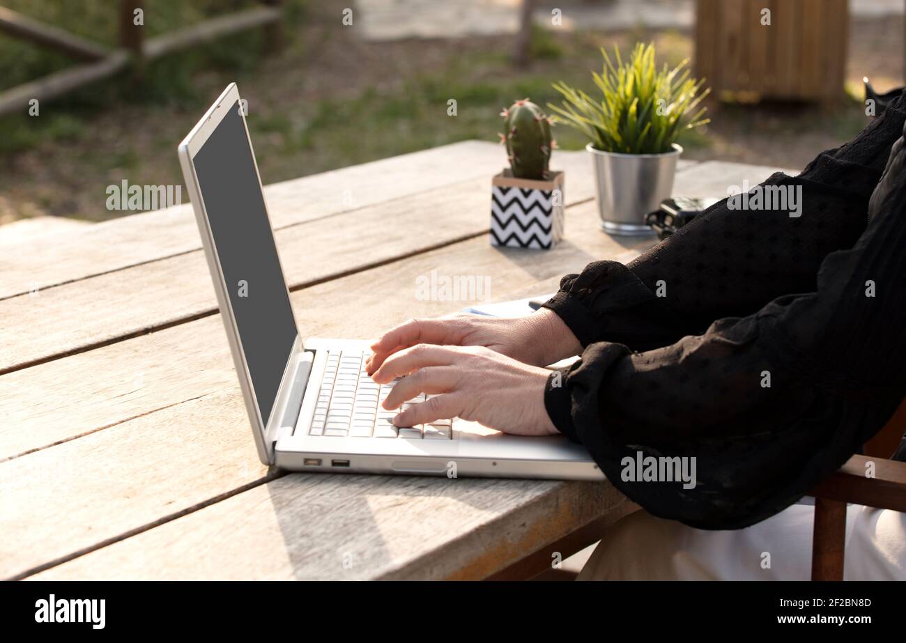 woman working virtually, outdoor work table with computer and forest in ...