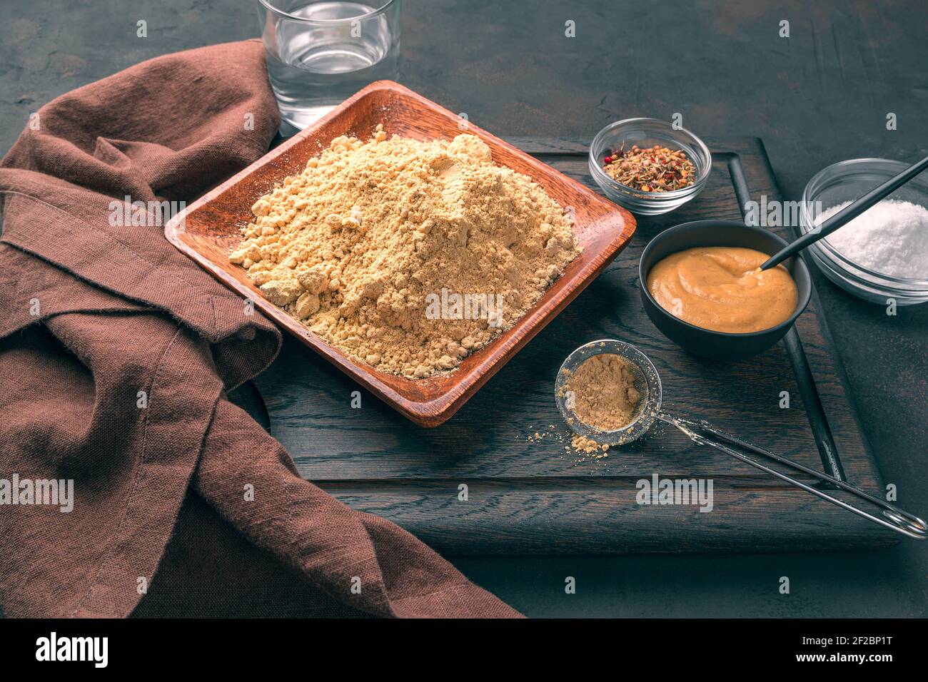 Mustard powder, ready-made mustard, salt, spices and water on a brown ...