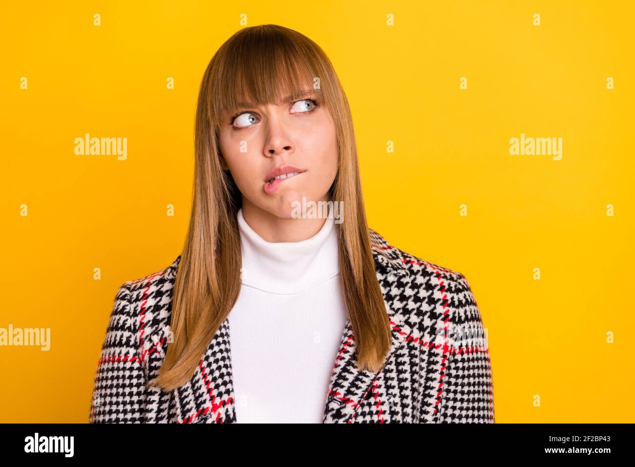 Portrait of worried young person biting lip look interested empty space ...