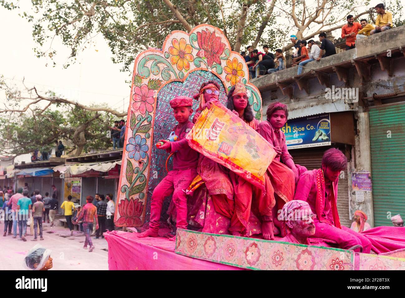 India, Mathura - Kids painted red on a float throwing colored powder ...