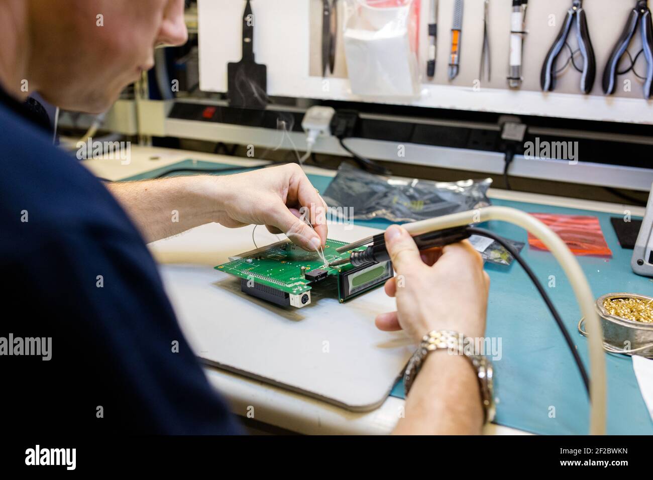 An unknown man using a soldering iron on a circuit board. Electronics ...