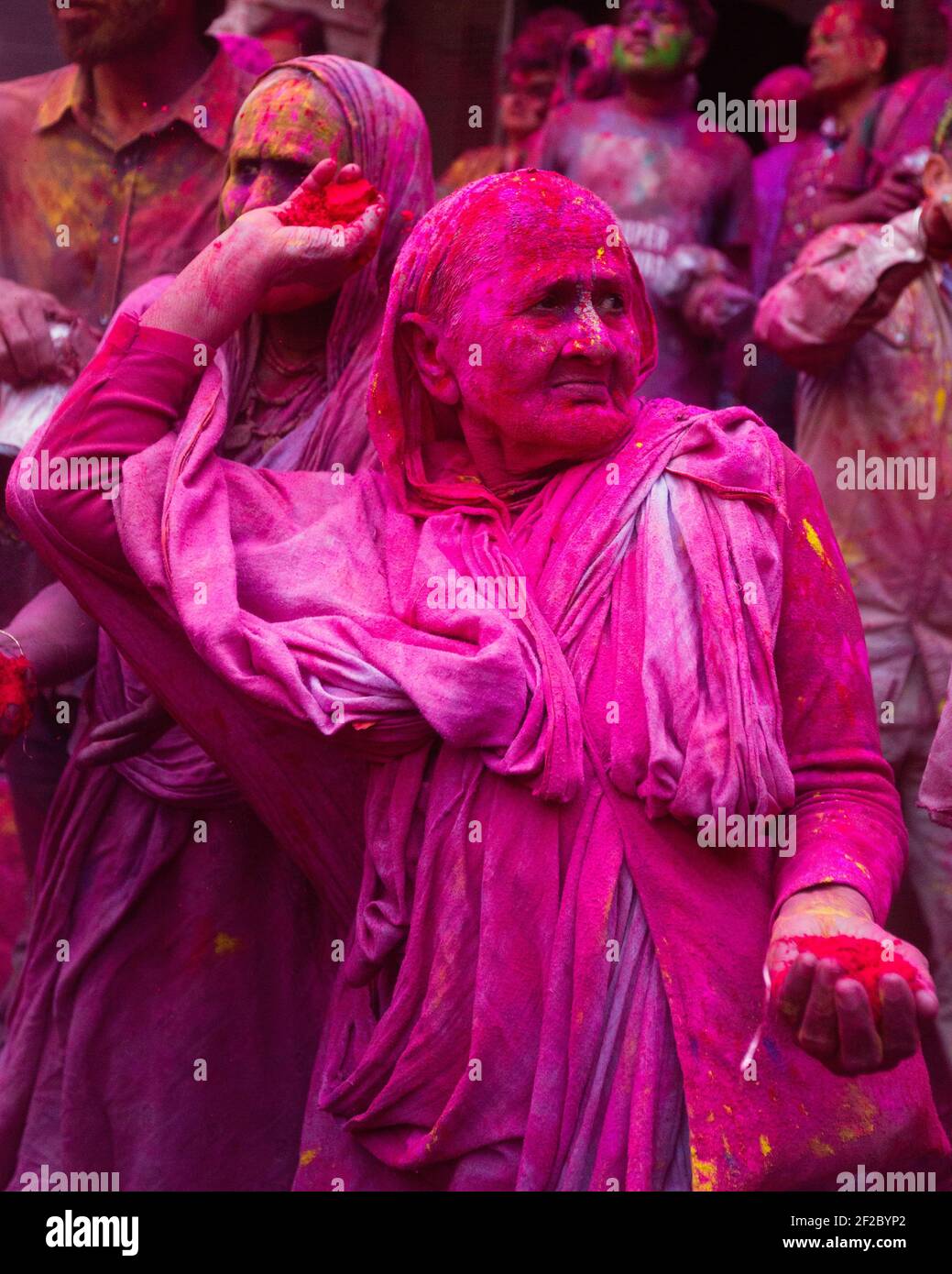 India, Vrindavan, Senior woman throwing colored powder at the widow's ...