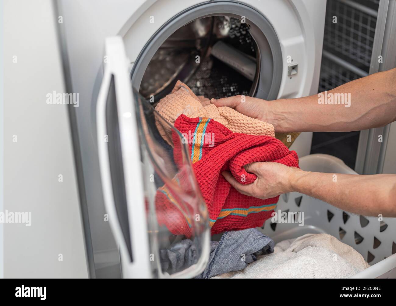 Close up view of man loading clothes to washing machine Stock Photo - Alamy