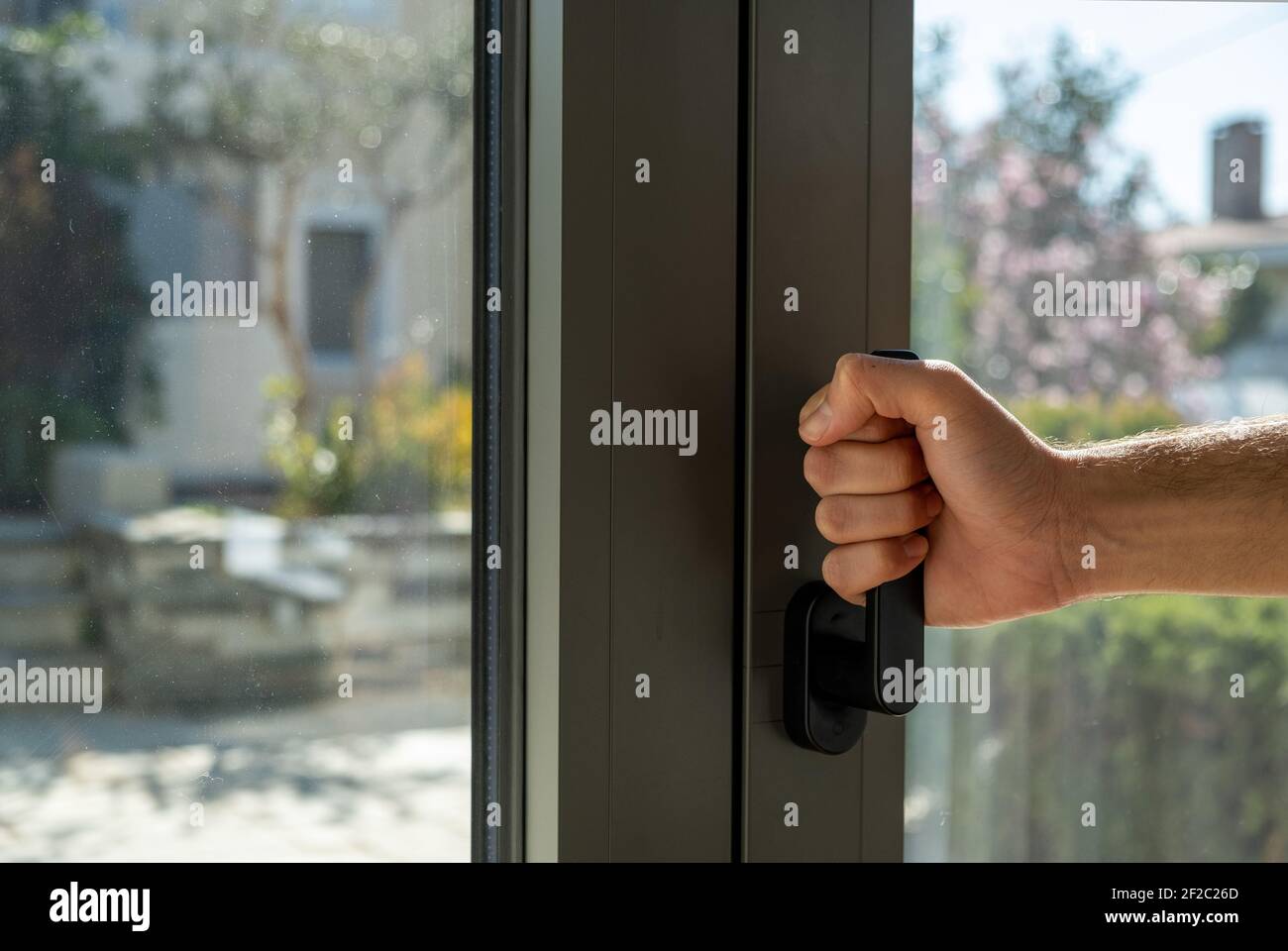 Hand holding aluminum window handle closeup view. Man opens or closes ...