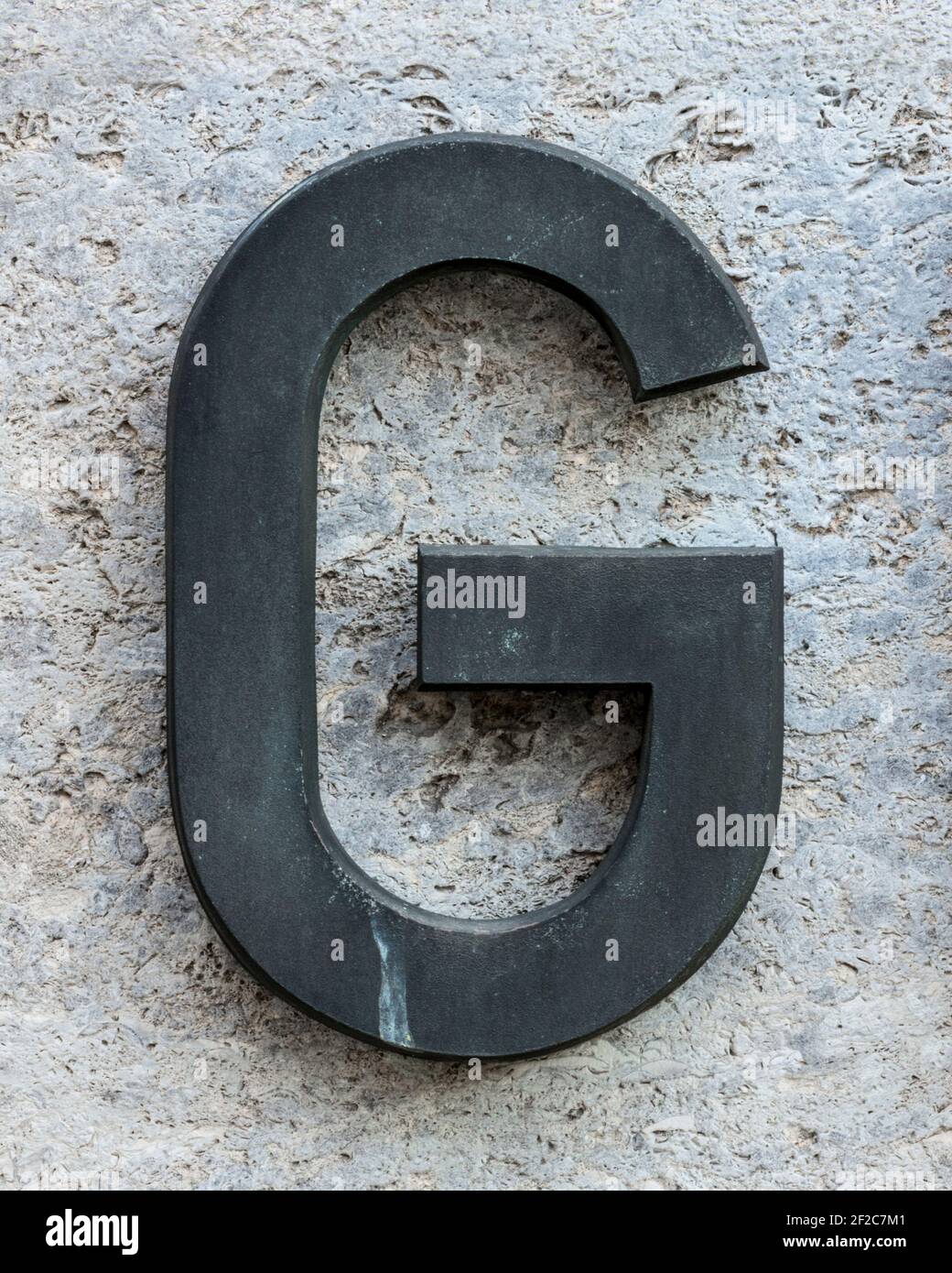 Metal letter G on a stone wall Stock Photo - Alamy