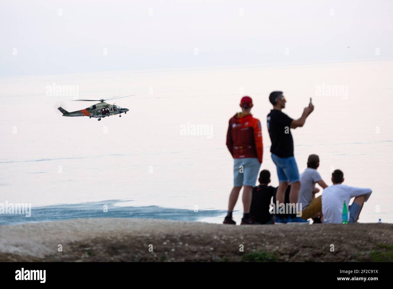 A group of tourists with a rescue helicopter flying overhead at ...