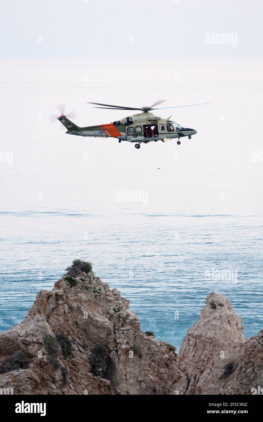 A rescue helicopter flying low over a jagged sea stack near Aphrodite's ...