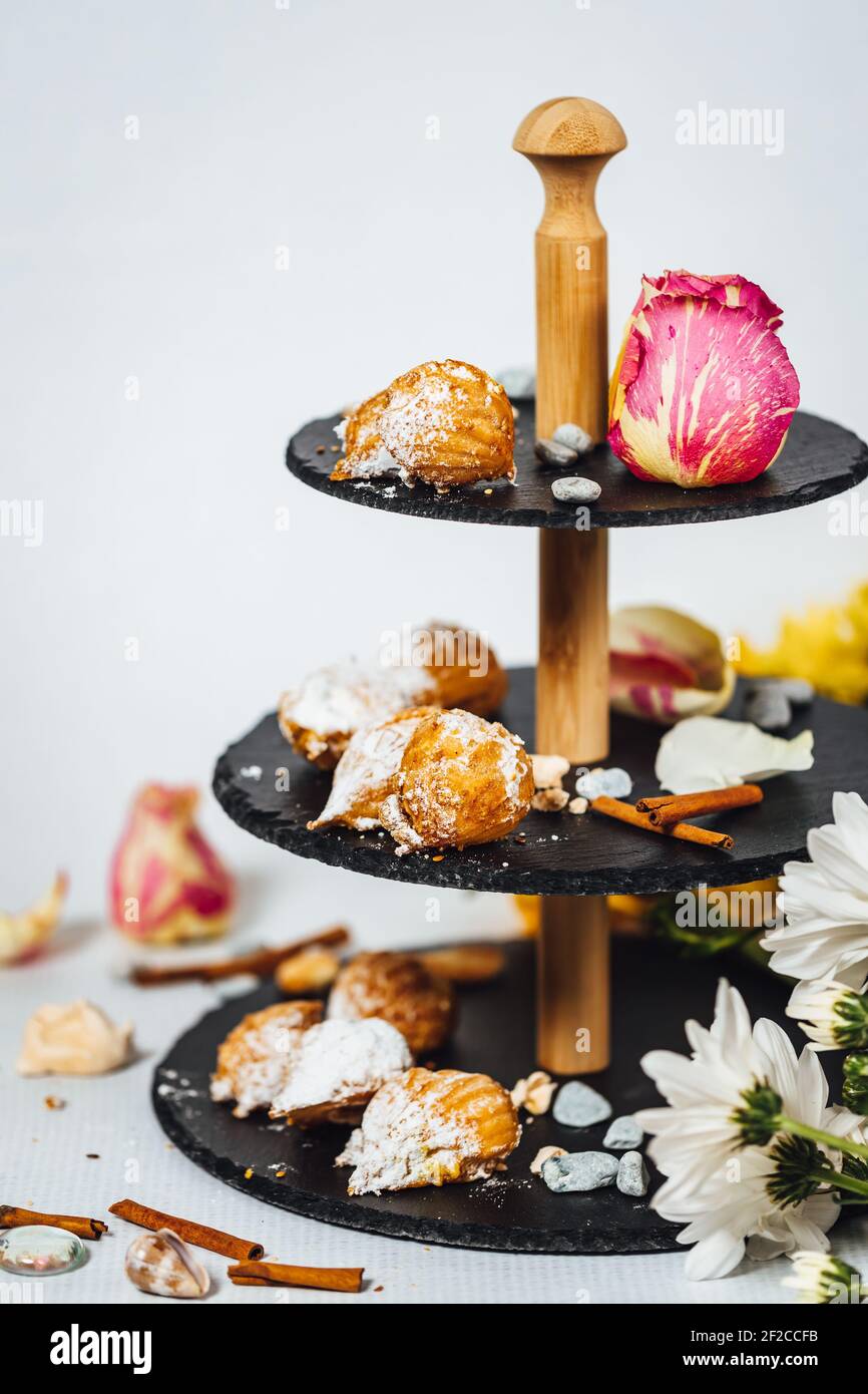 A vertical shot of various types of cakes and biscuits on a cake stand ...