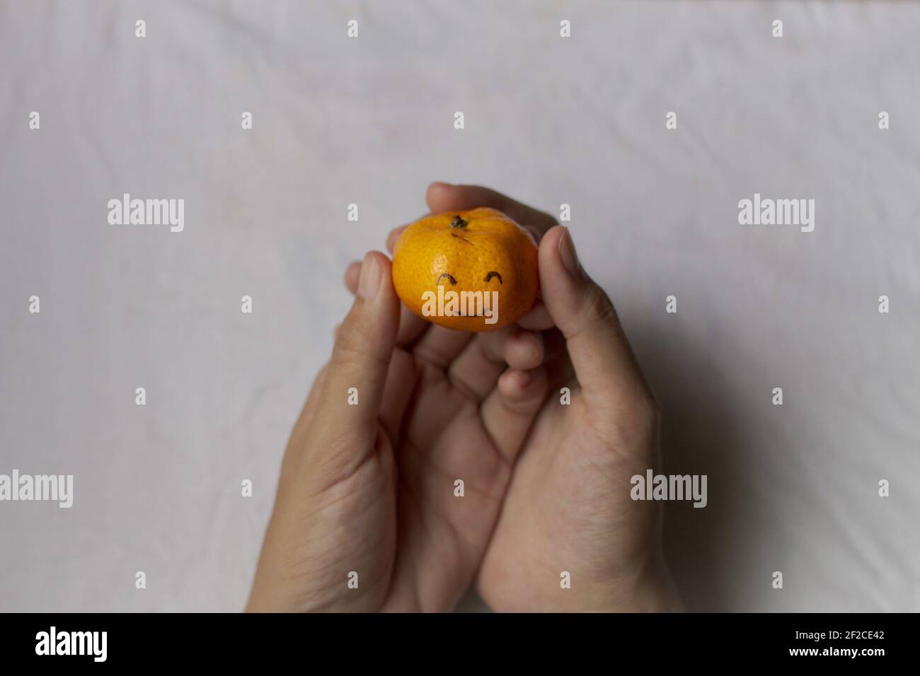 A top view of a fresh tangerine with a funny face in a hands Stock ...