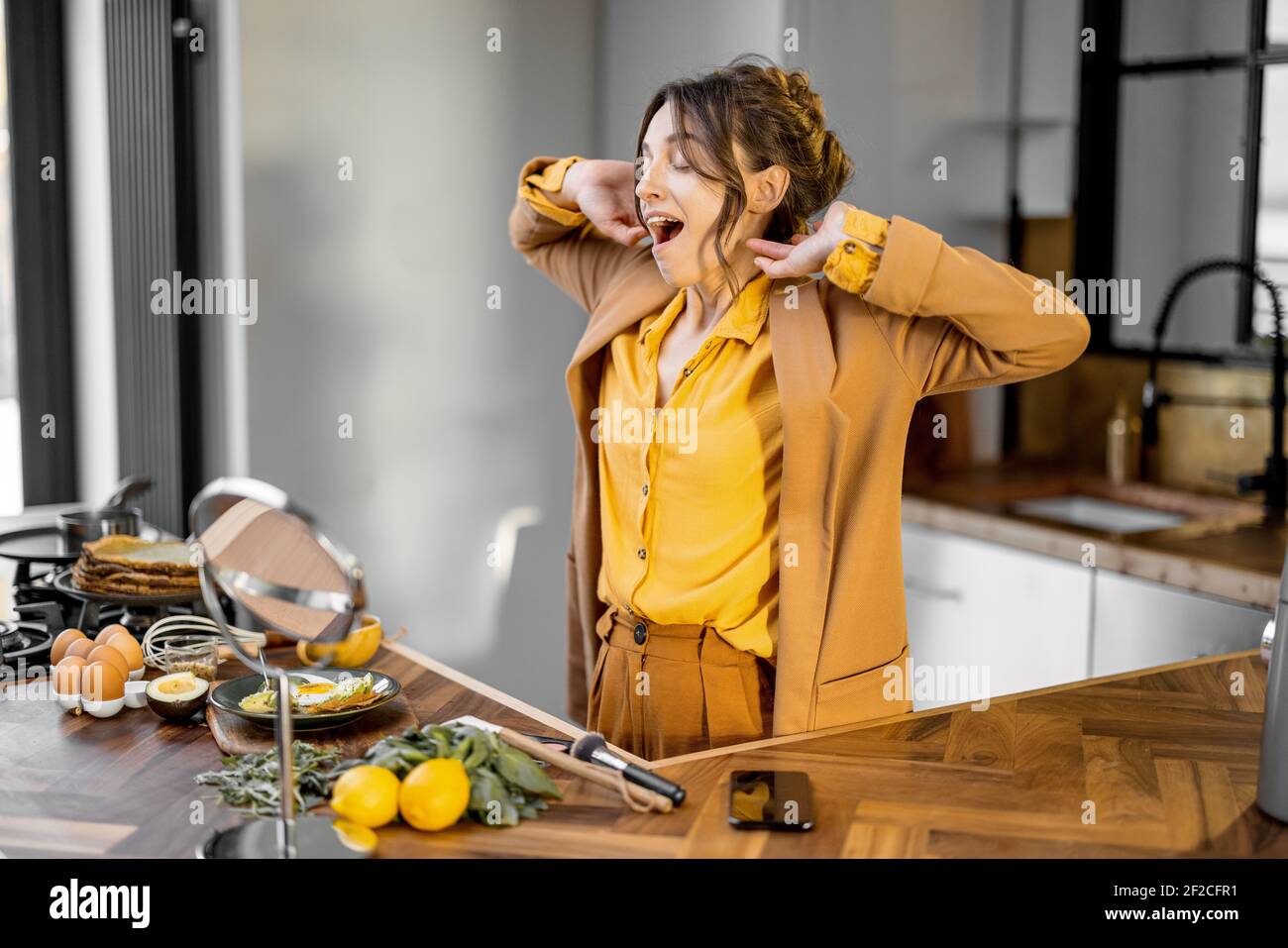 Sleepy businesswoman wakes up, stretching on the kitchen while having a ...
