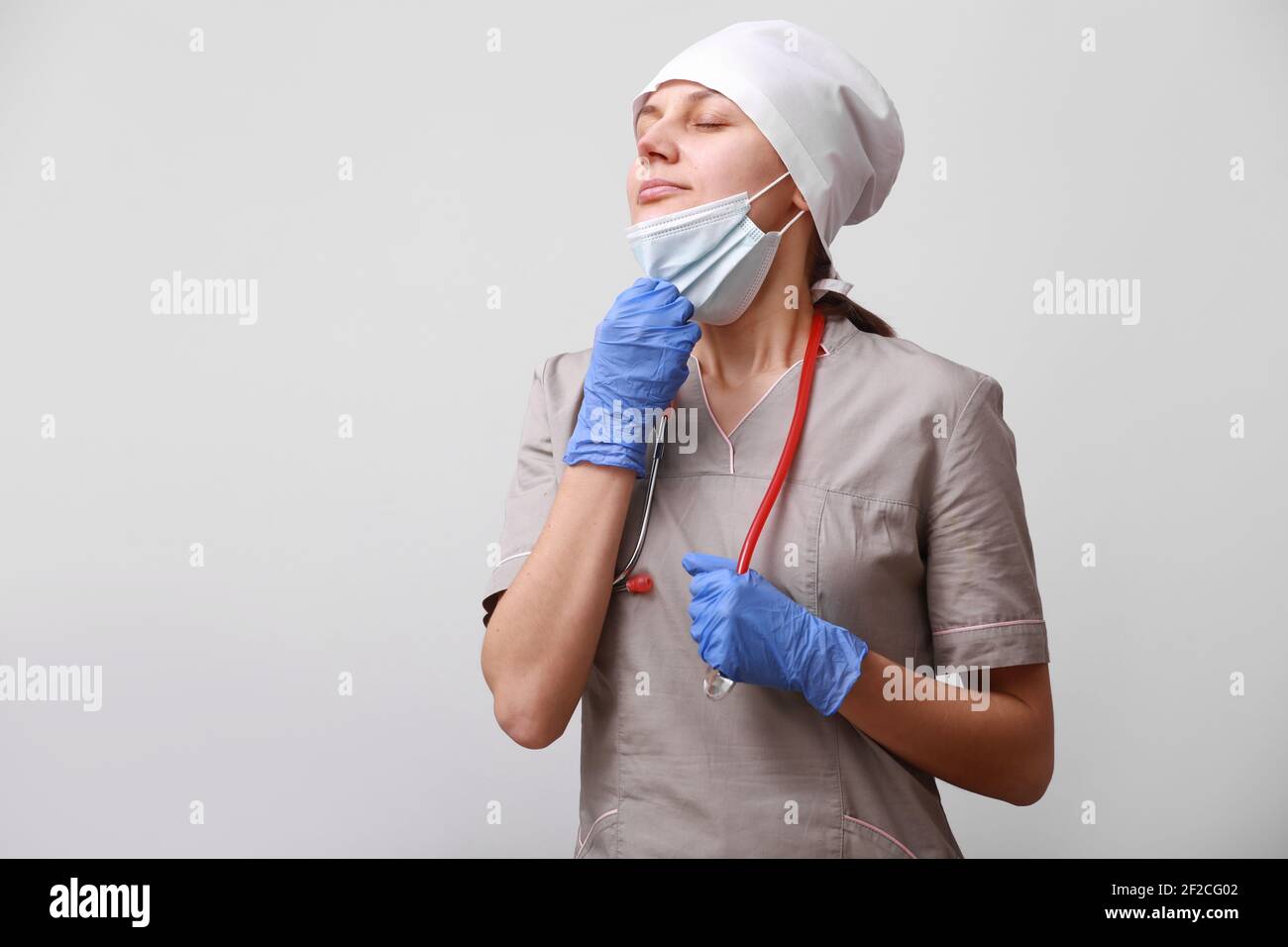 smiling female doctor with stethoscope in uniform. Woman is taking off ...