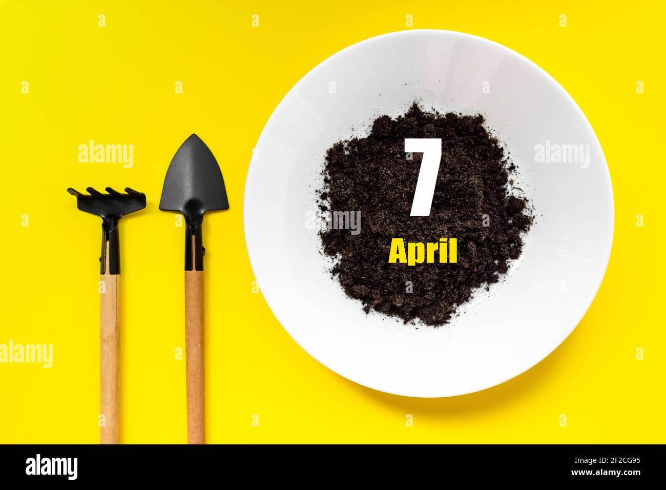 April 7th. Day 7 of month, Calendar date. White plate of soil with a ...