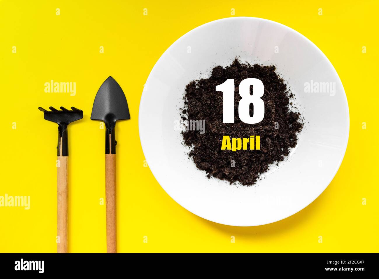 April 18th. Day 18 of month, Calendar date. White plate of soil with a ...