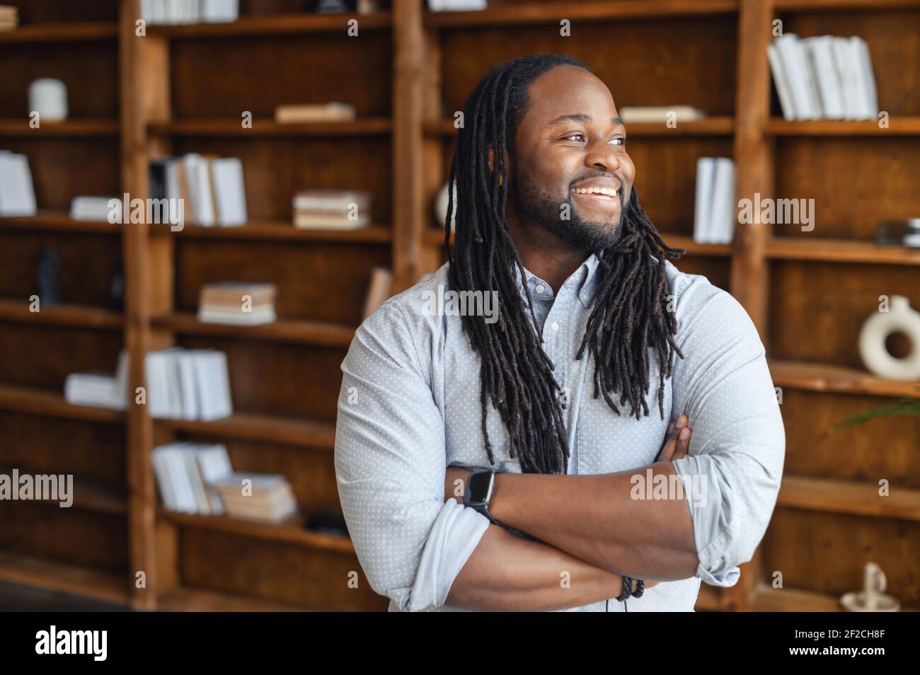 Smiling African office employee with dreadlocks in smart casual wear ...