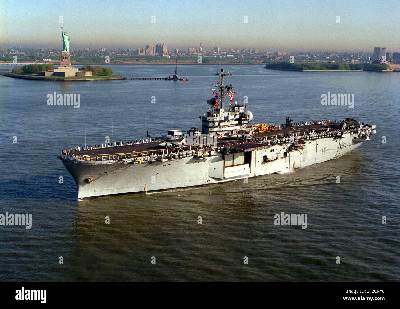 Port side view of USS Guadalcanal (LPH-7) passing Statue of Liberty ...