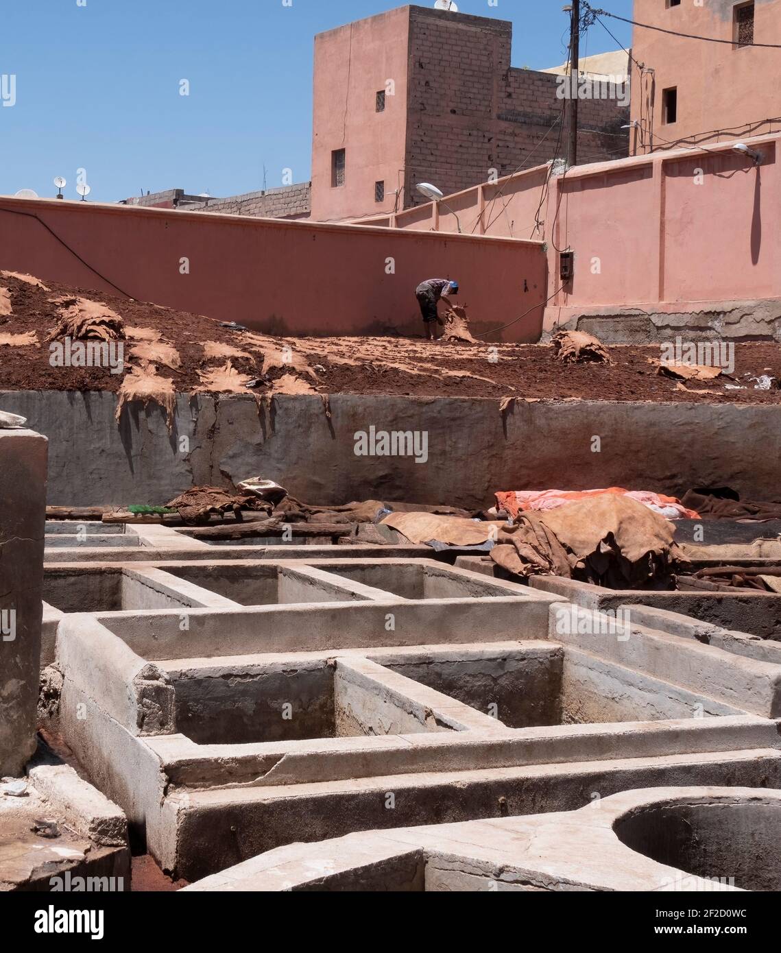 MARRAKESH, MOROCCO- JUNE, 10, 2019: a worker and vats for tanning ...