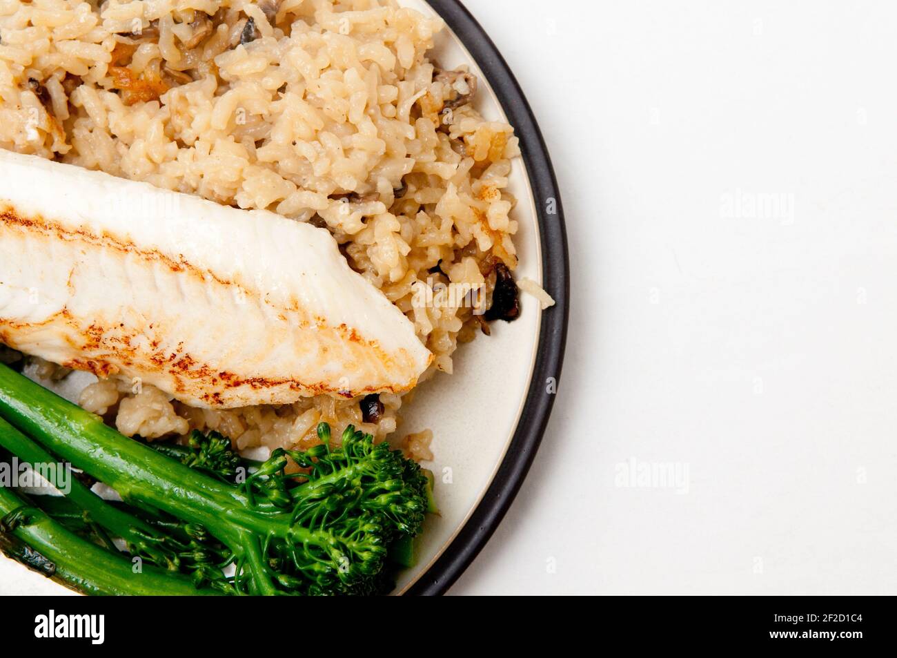 A plate of roasted fish fillet, rice with mushrooms, and broccolini ...