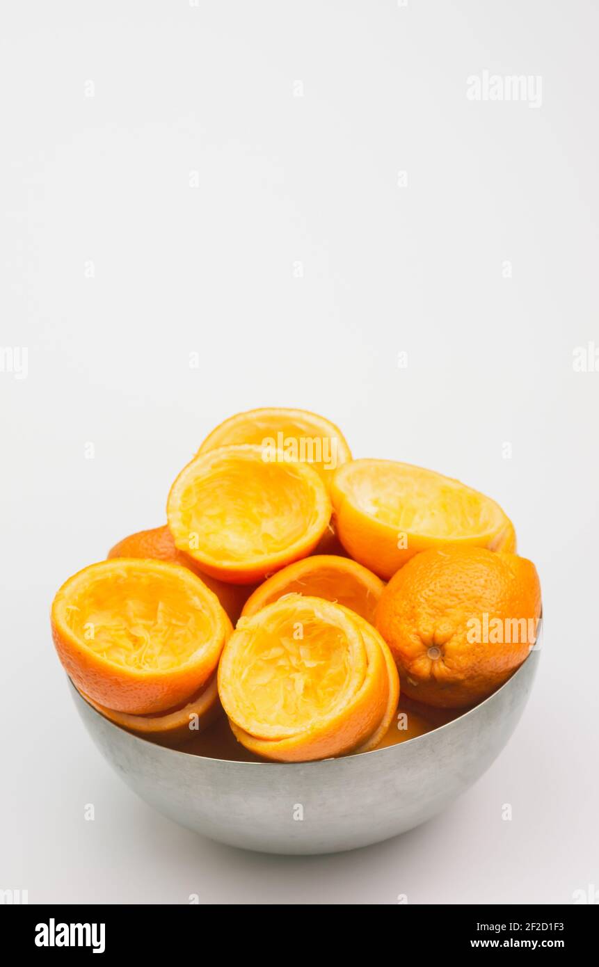 A vertical shot of orange peels in a metal bowl on a white background ...