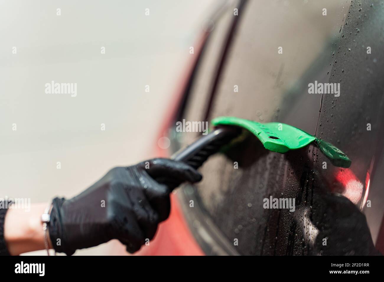 Removal of water from the glass with a rubber scraper after washing the ...