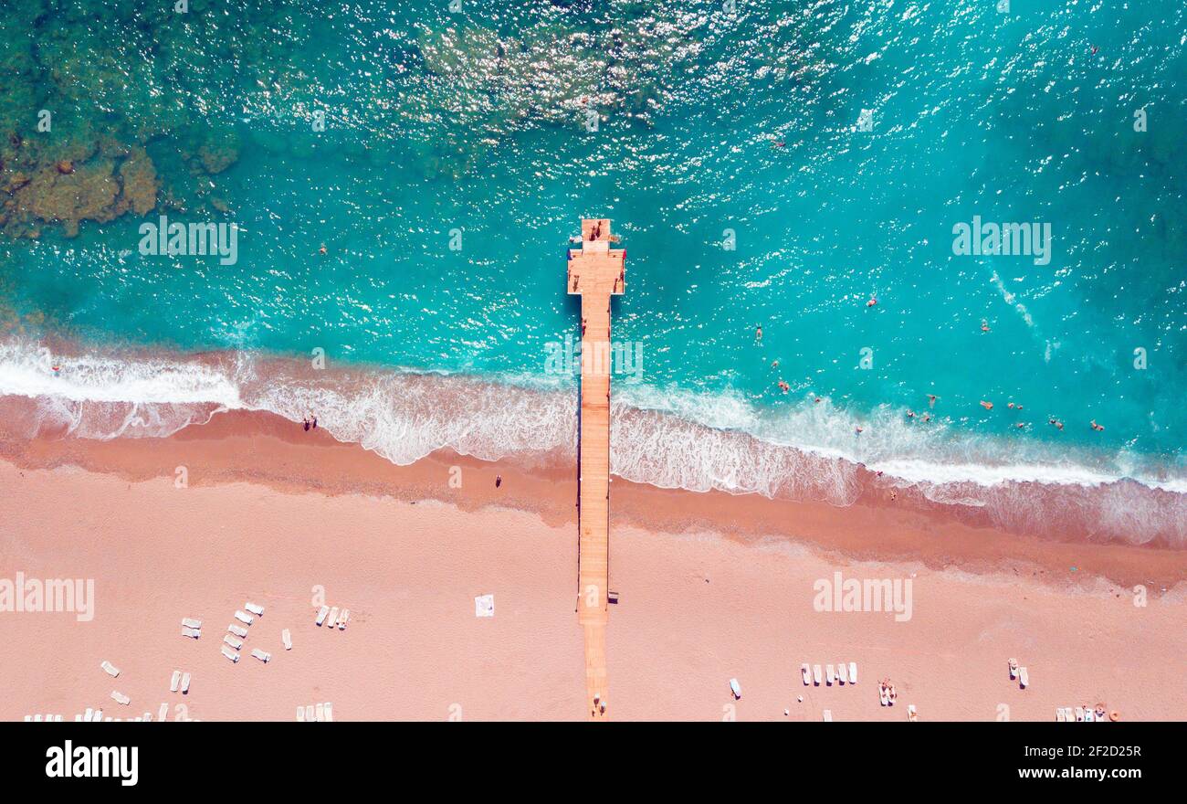 An aerial shot of a dock on the sea surrounded by a beach under the ...