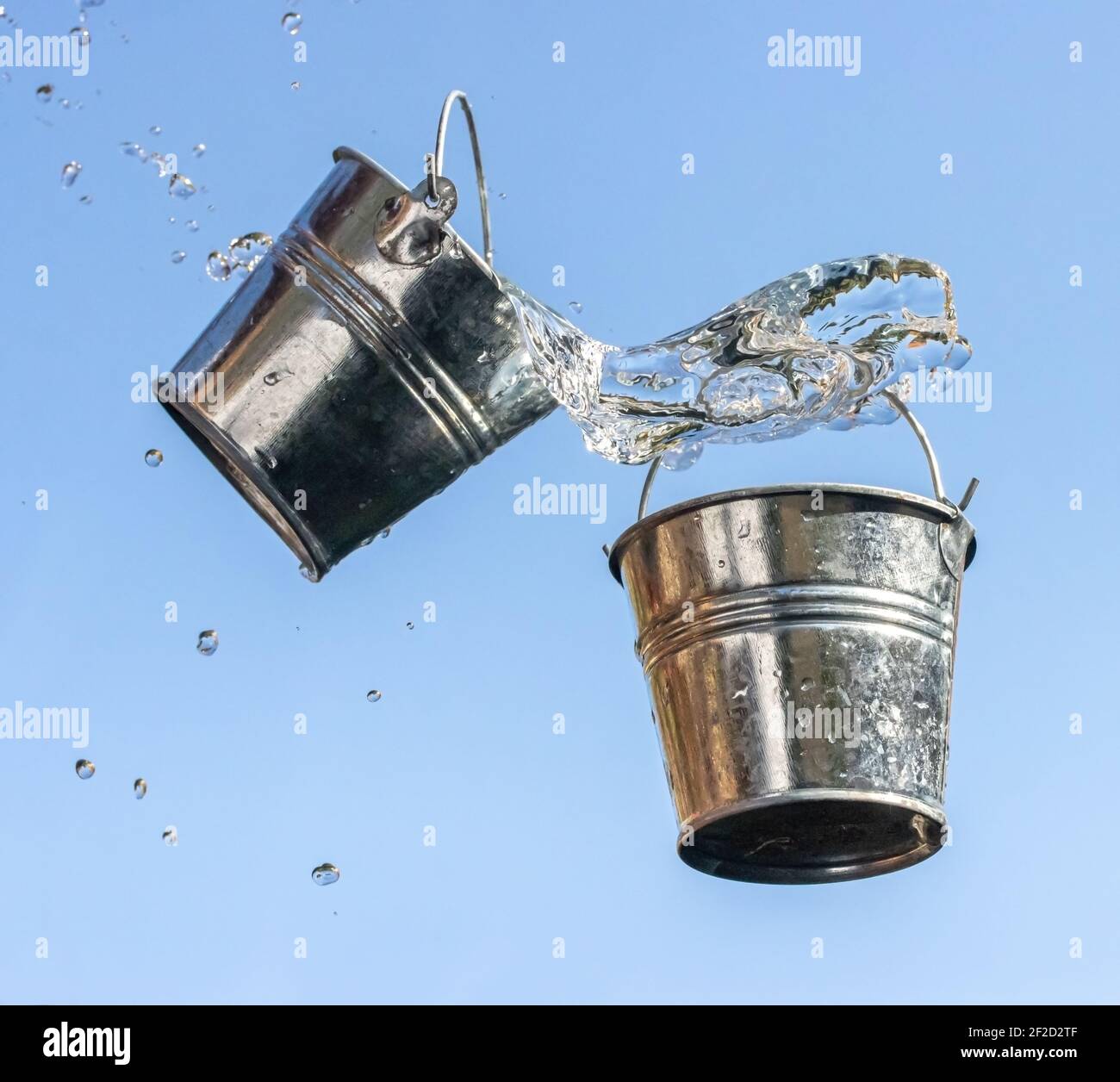A pouring water from falling bucket to bucket, on a background of blue ...